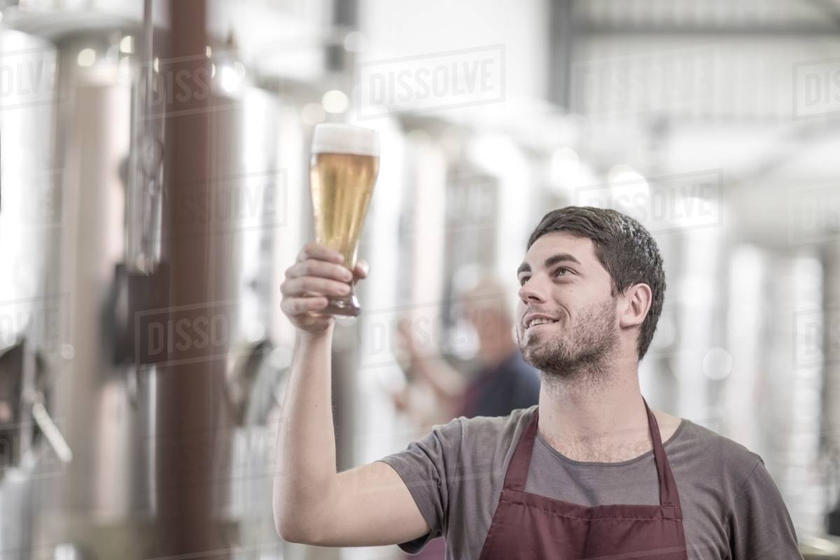 Brewer in brewery holding up a glass of beer - Royalty-free Stock Photo ...