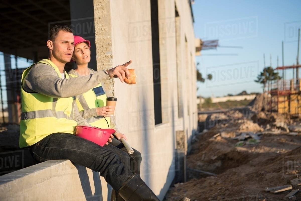 Builder and architect pointing and looking out from window frame on ...