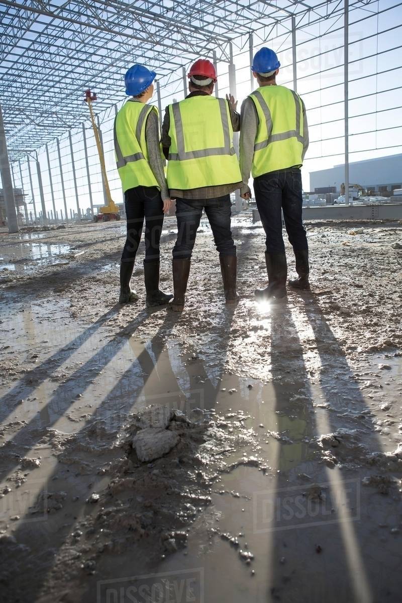 Rear view of architect and builders meeting on construction site ...