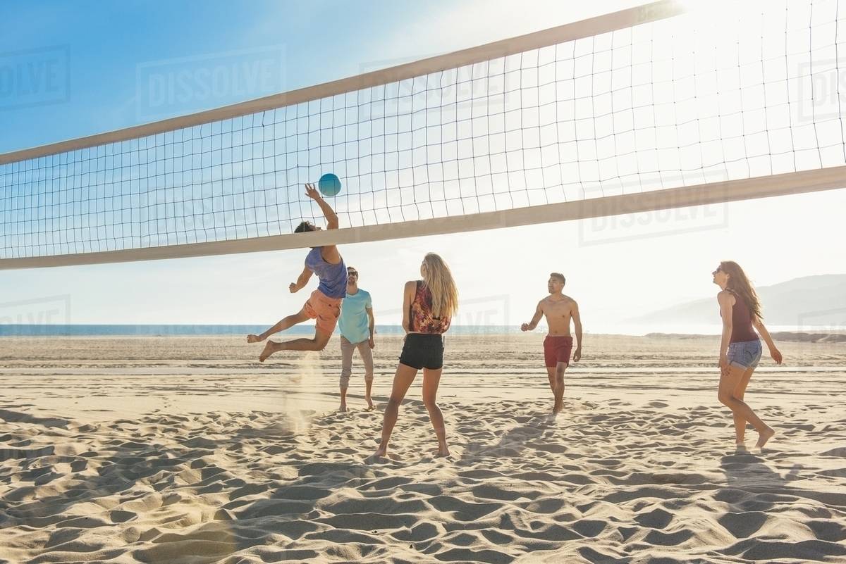 Group of friends playing volleyball on beach - Stock Photo - Dissolve