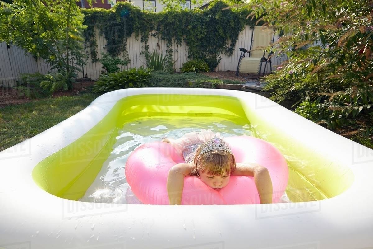 Girl lying on inflatable floating in pool - Stock Photo - Dissolve