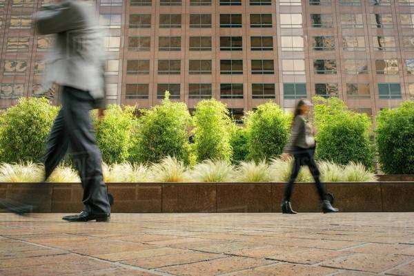 Businessman and woman walking in opposite directions - Stock Photo ...