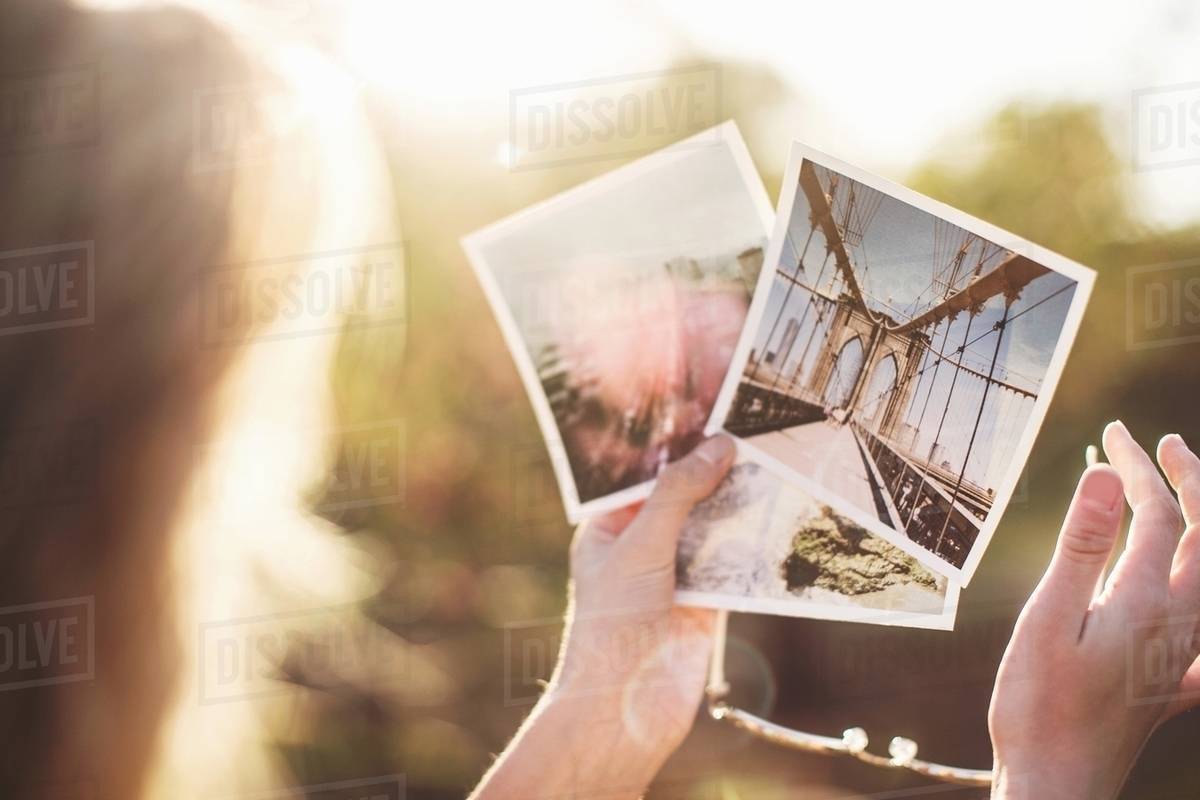 High angle view over shoulder of young woman holding photographs ...