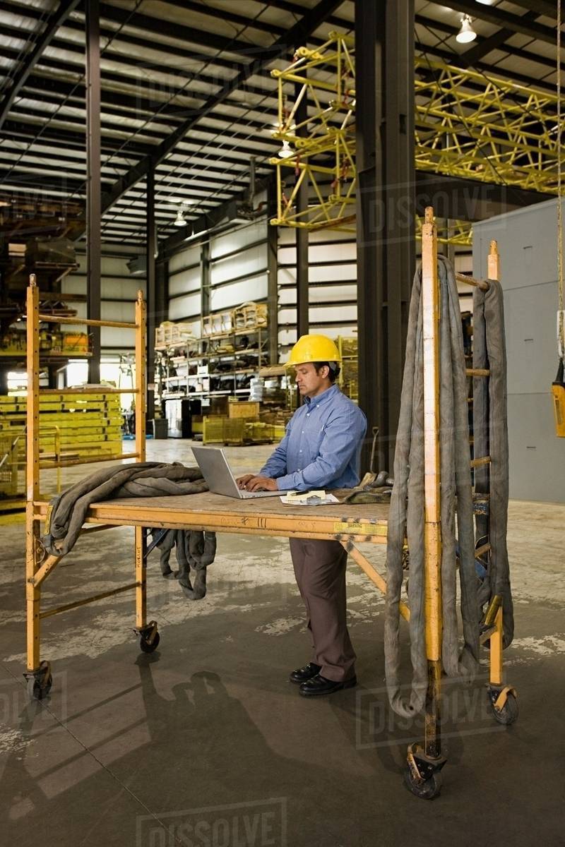 Man in warehouse with laptop - Stock Photo - Dissolve
