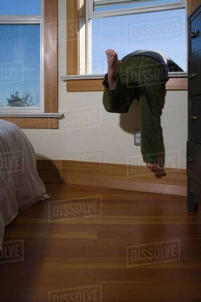 Boy climbing out of window - Stock Photo - Dissolve