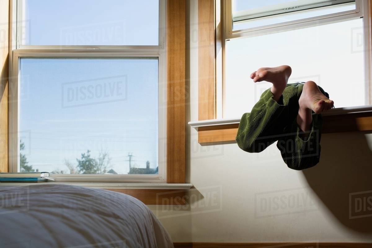 Boy climbing out of window - Stock Photo - Dissolve
