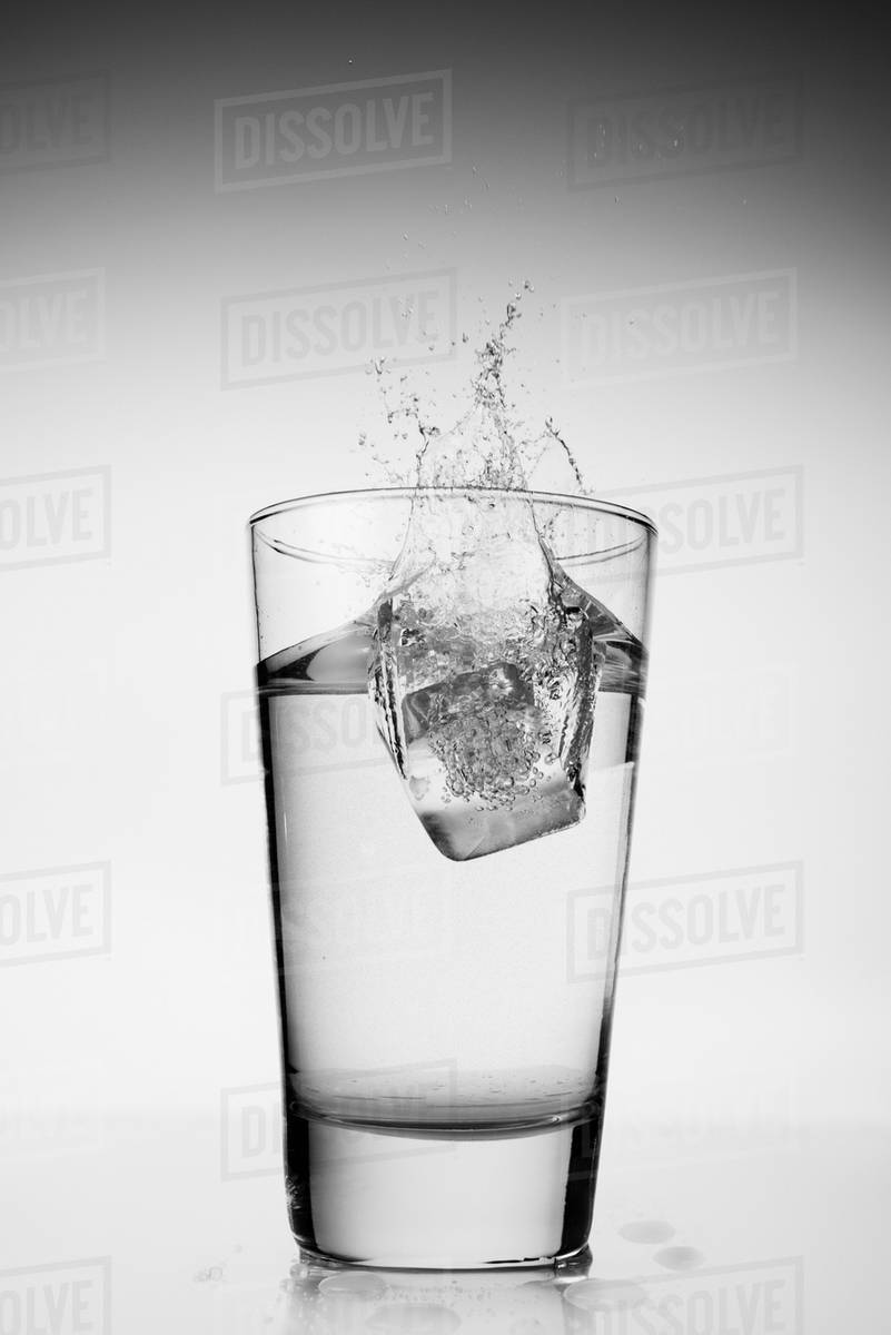 Ice cube falling into glass of water - Royalty-free Stock Photo | Dissolve