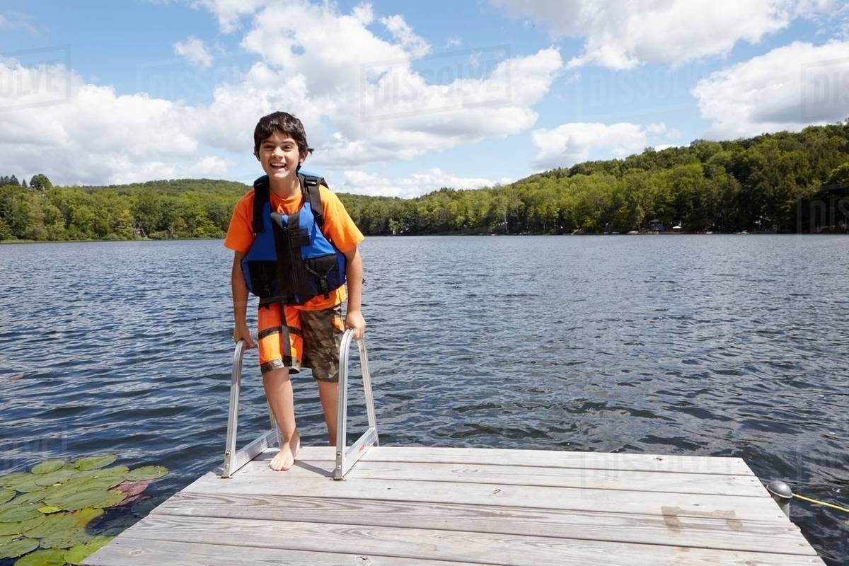 Boy on pier by lake, New Milford, Pennsylvania, US - Stock Photo - Dissolve