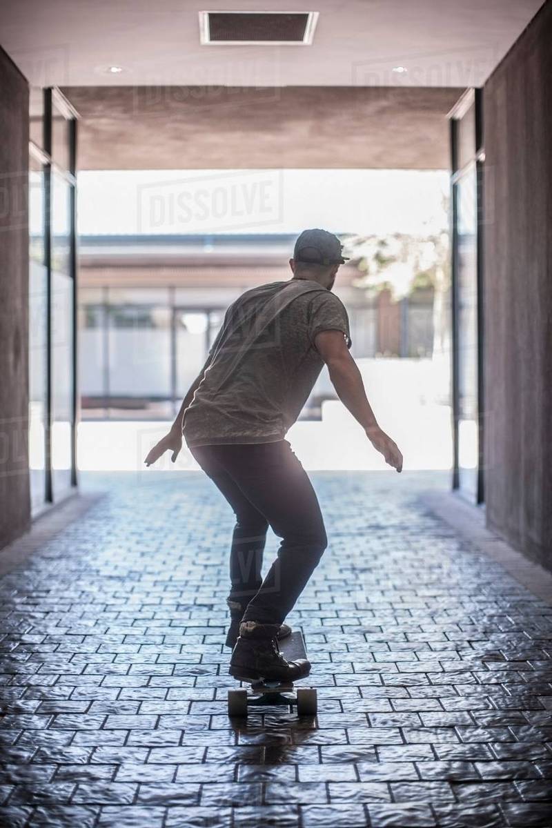 Rear view of young male skateboarder skateboarding in city - Stock ...