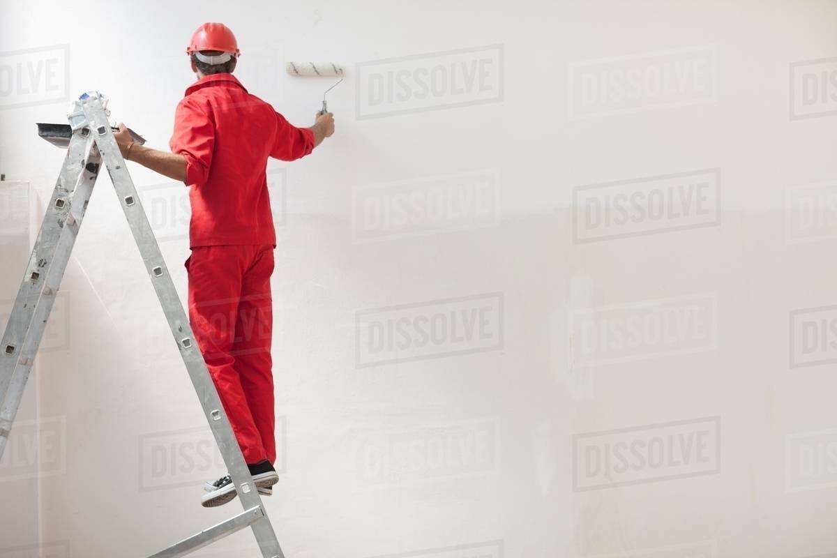 Decorator on step ladder painting white wall - Royalty-free Stock Photo ...