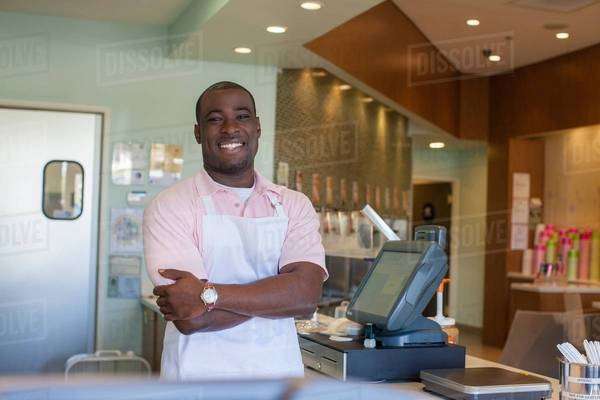 Cashier smiling behind counter - Stock Photo - Dissolve