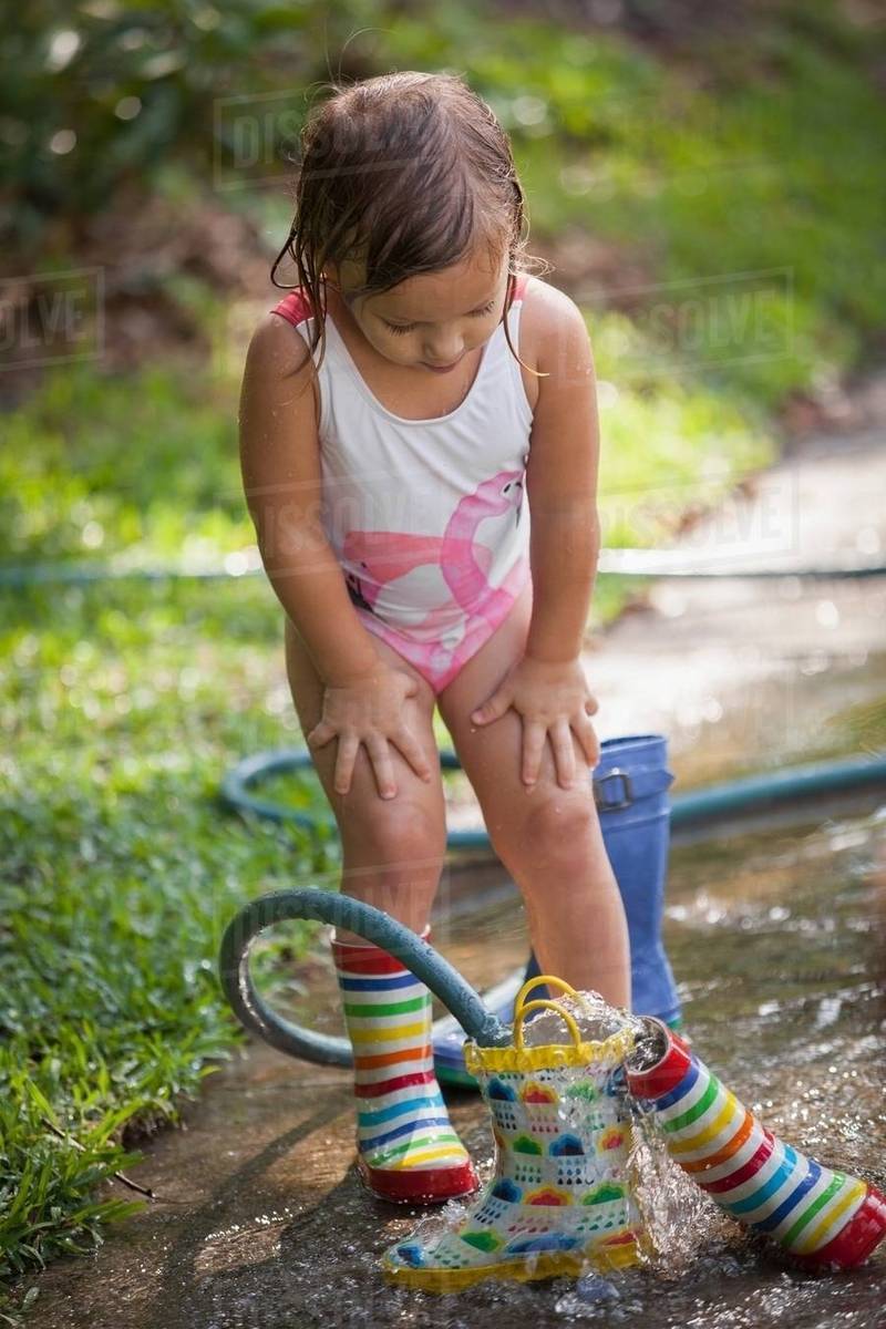 Child filling wellies with water from hose - Royalty-free Stock Photo ...