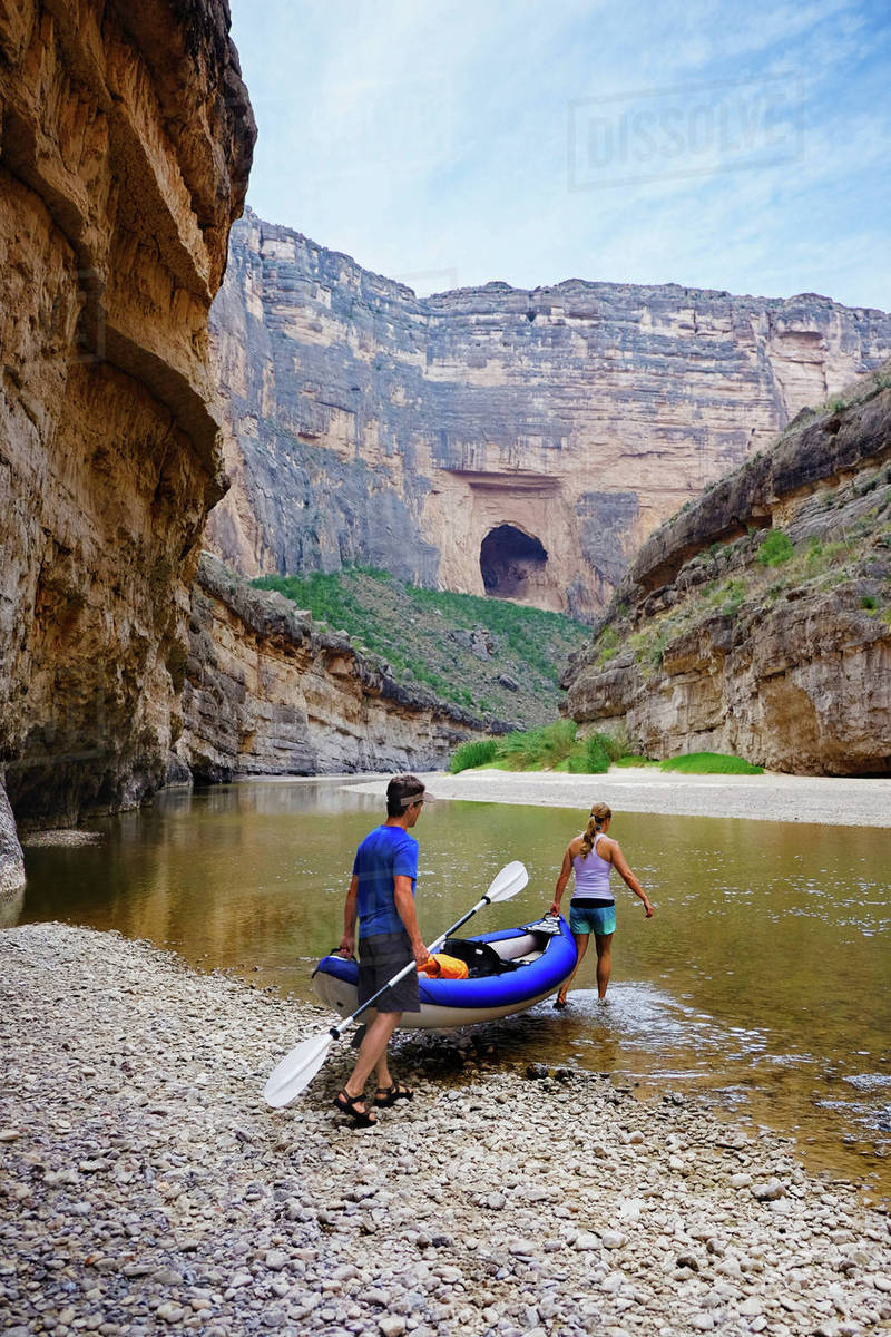 Couple carrying kayak into river, Big Bend National Park, Texas ...