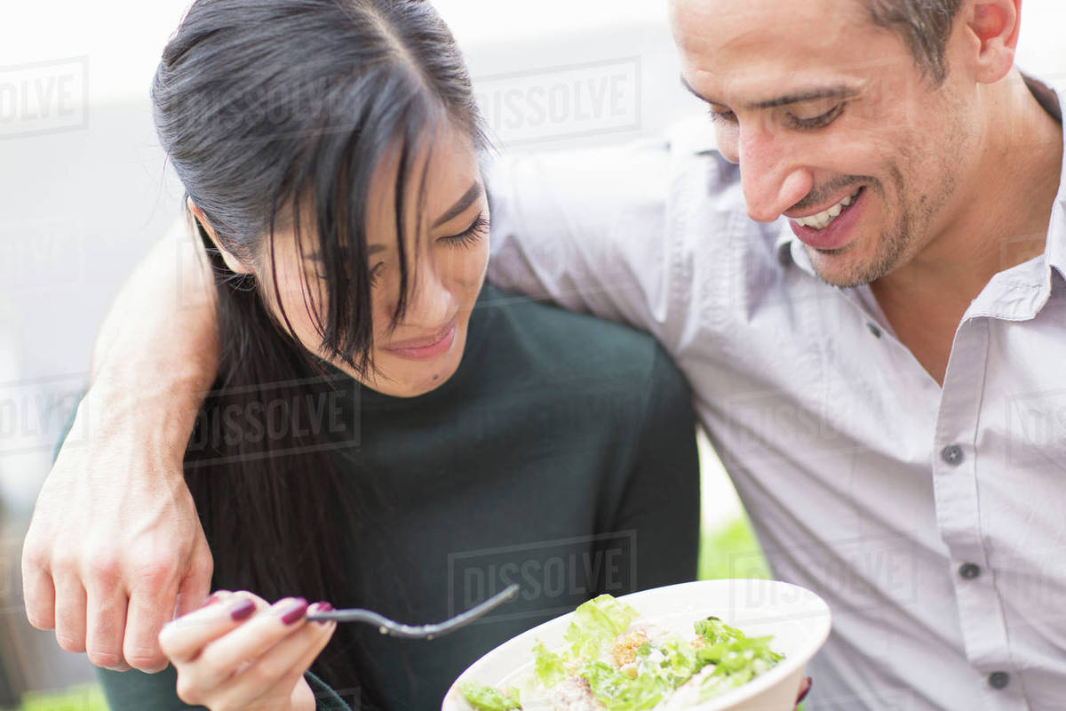 Couple sharing lunch looking down smiling - Royalty-free Stock Photo ...