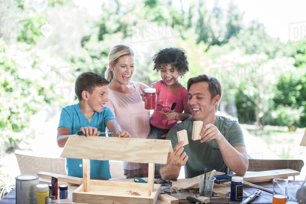 Family doing crafts together, making birdhouse - Stock Photo - Dissolve