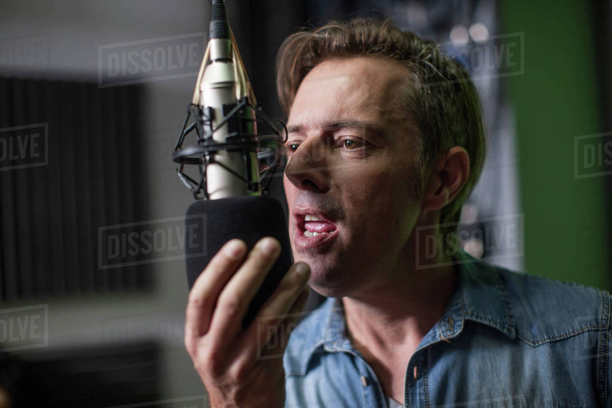 Man singing into microphone in recording studio - Stock Photo - Dissolve