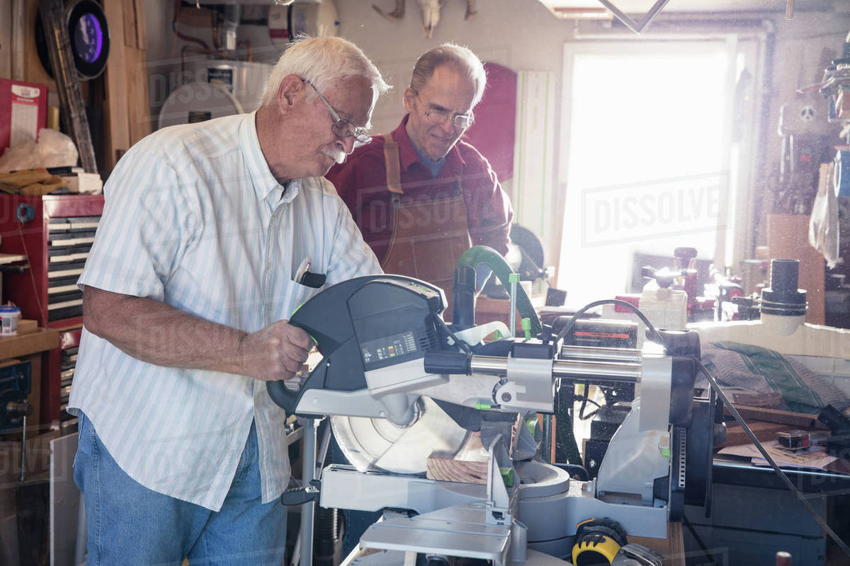 Senior men sawing woodblock in carpentry workshop - Stock Photo - Dissolve