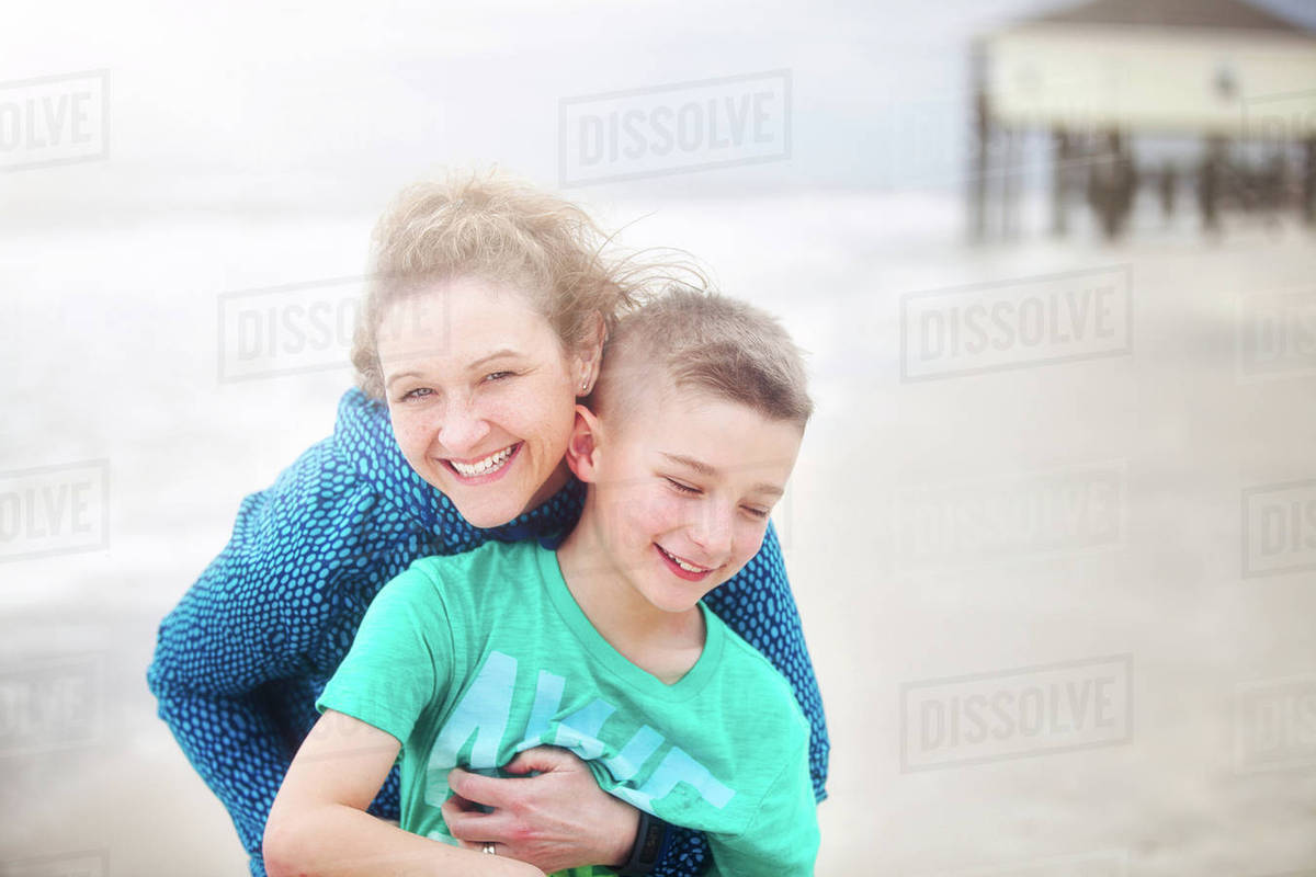 Woman hugging boy on beach - Stock Photo - Dissolve