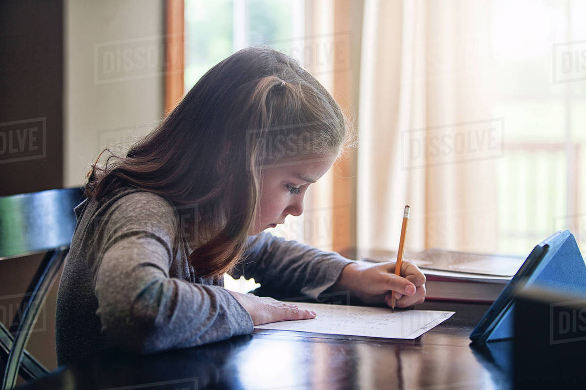 Side view of girl at desk writing - Royalty-free Stock Photo | Dissolve
