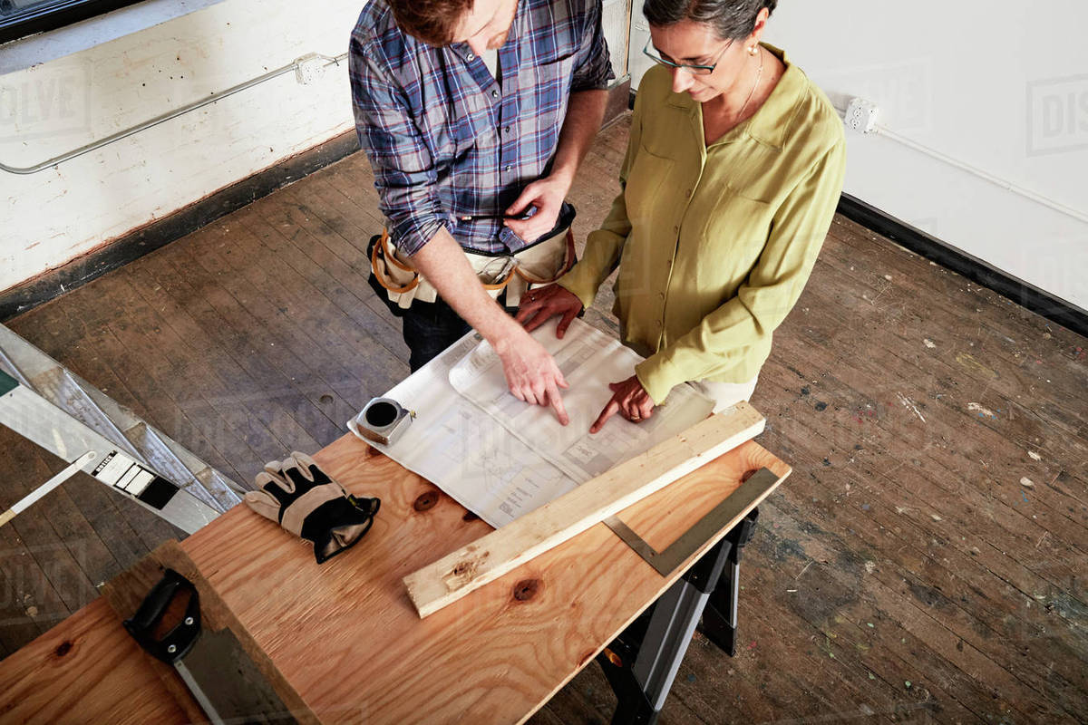 Carpenter looking at blueprint with client - Royalty-free Stock Photo ...