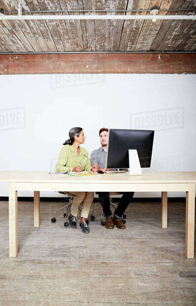 Colleagues at desk behind computer monitor - Royalty-free Stock Photo ...