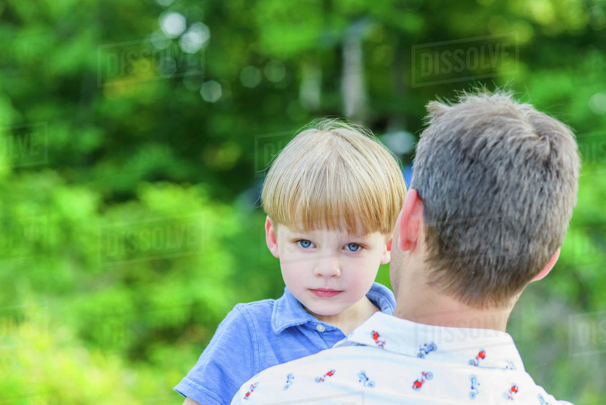 Boy looking at camera over fathers shoulders - Royalty-free Stock Photo ...