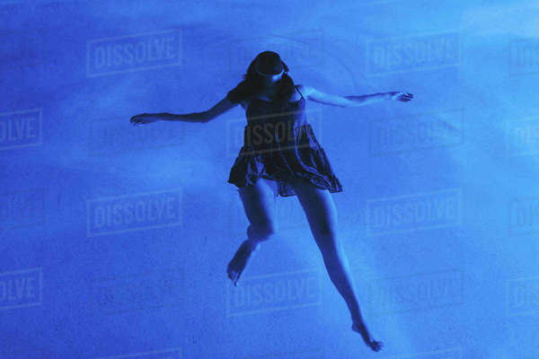 Woman floating in pool - Stock Photo - Dissolve