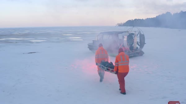 Team of rescuers in orange uniform loading victim lying on stretchers ...