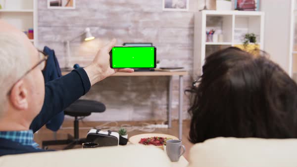 Back view of elderly age couple looking at phone with green screen ...