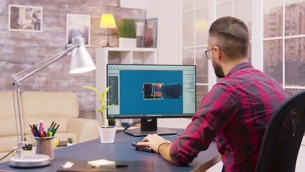 Over the shoulder shot of young game developer working from home while ...