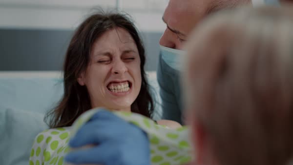 Close up of pregnant woman pushing and screaming in hospital ward at ...