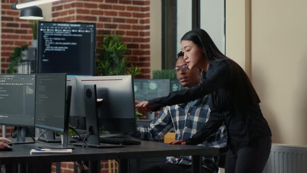 Two software developers holding laptop with coding interface walking ...