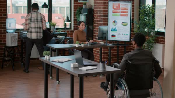 Man working in disability friendly office with business charts and ...