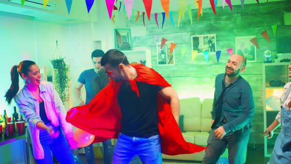 Cheerful young man wearing a superhero red cape showing his dancing ...