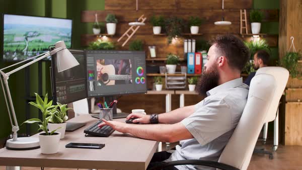Male editor working in post production studio. In the background - the ...