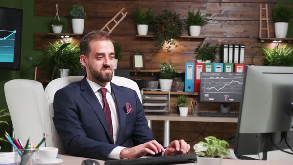 Zoom in footage of handsome guy in suit working alone in modern office ...