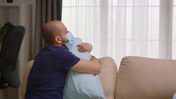 Man infected with covid-19 wearing a mask and hugging a pillow during ...