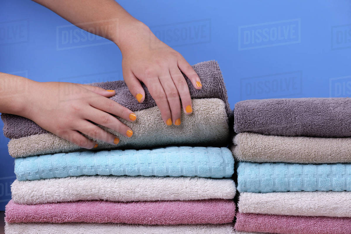 A studio concept photo of female hands reaching for a folded towel ...