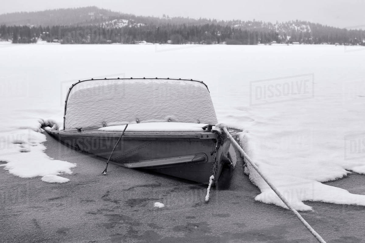 A b&w image of an old boat sunken into the ice of Hauser Lake, Idaho in ...