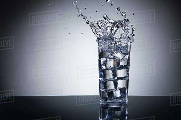 Ice being dropped into a glass of water making a splash. - Royalty-free ...