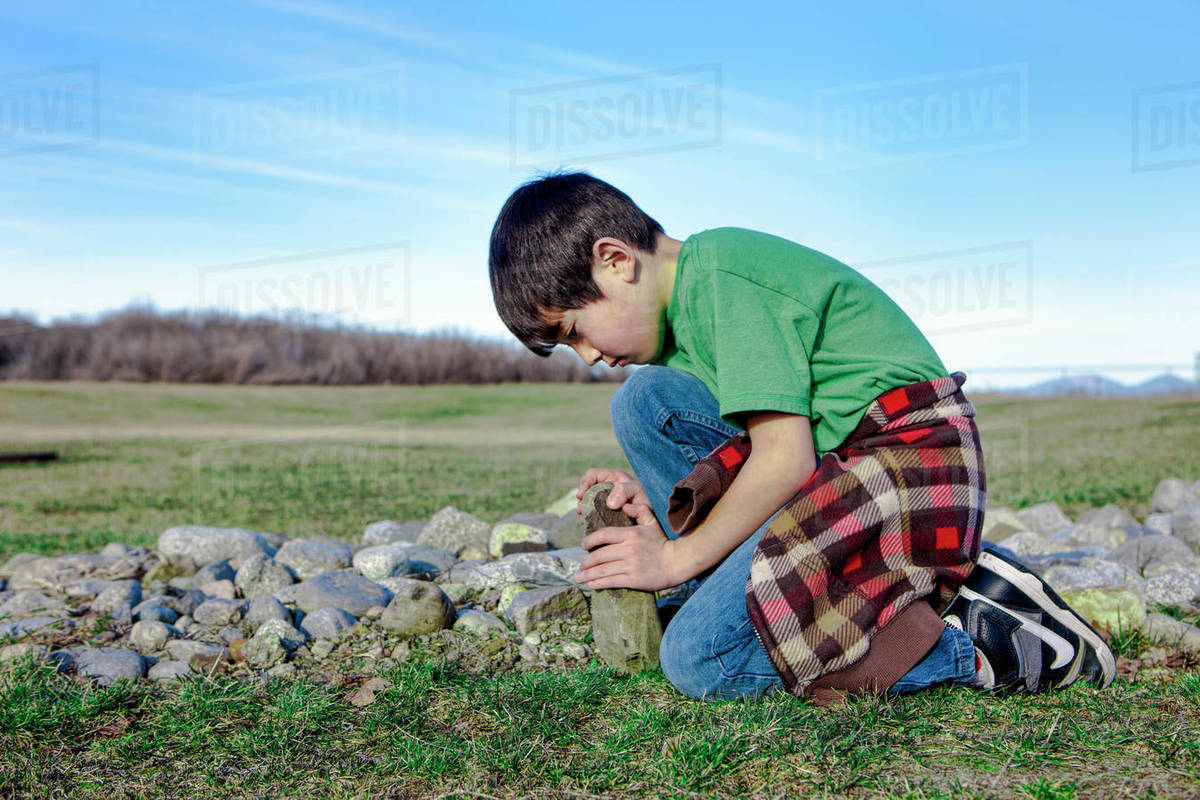 A young boy looks under a rock to see what is under there. - Royalty ...