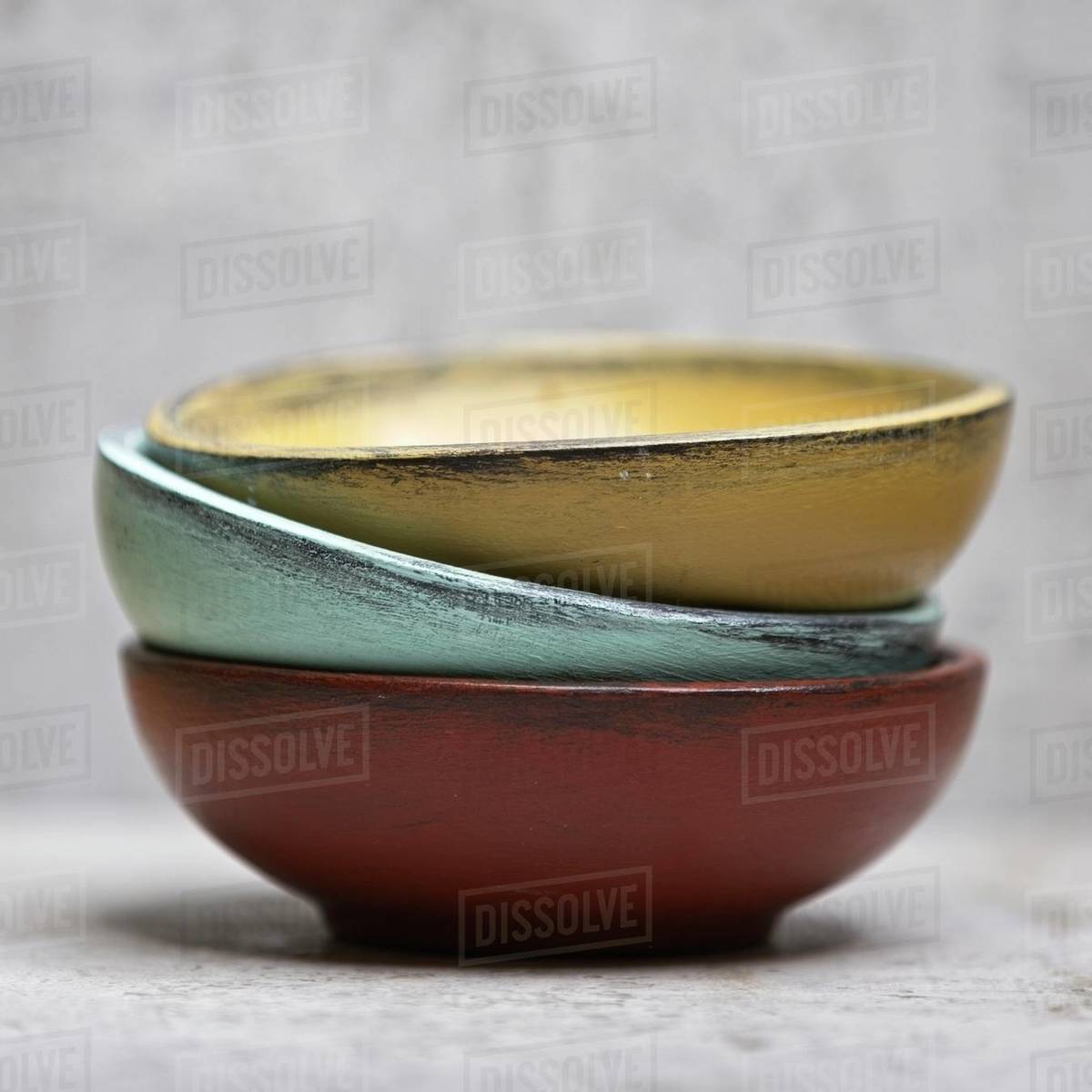 A close up studio photo of three different colored wooden bowls stacked ...