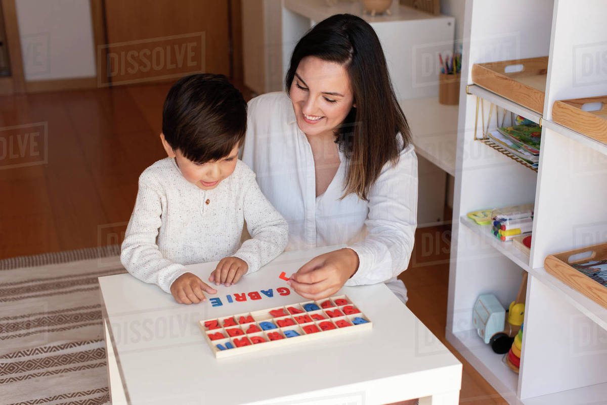 Little Kid learning to write and read with a alphabet and mother or ...