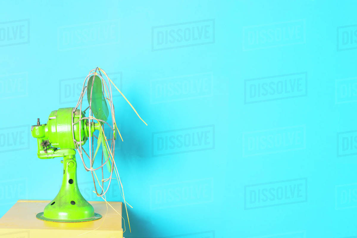Antique green colored fan with blue background - Stock Photo - Dissolve