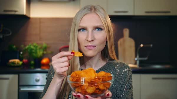 Glad woman eating potato chips. Beautiful young female enjoying potato ...
