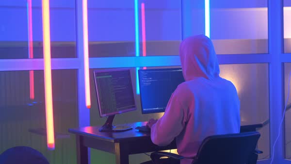 Back view of Hacker in white hoodie penetrating network system in neon ...