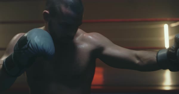 Caucasian shirtless sweaty strong male boxer in gloves punching bag ...