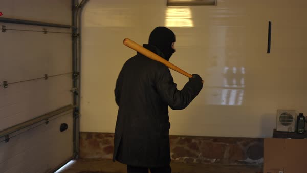 Empty garage with suspicious cautious male robber passing with baseball ...