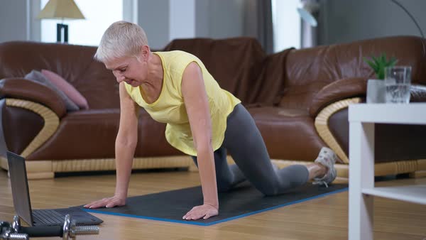 Middle aged fit woman training flexibility on snake position in slow ...