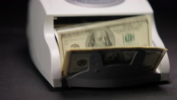 Close-up banknote counting machine with Caucasian female finger ...